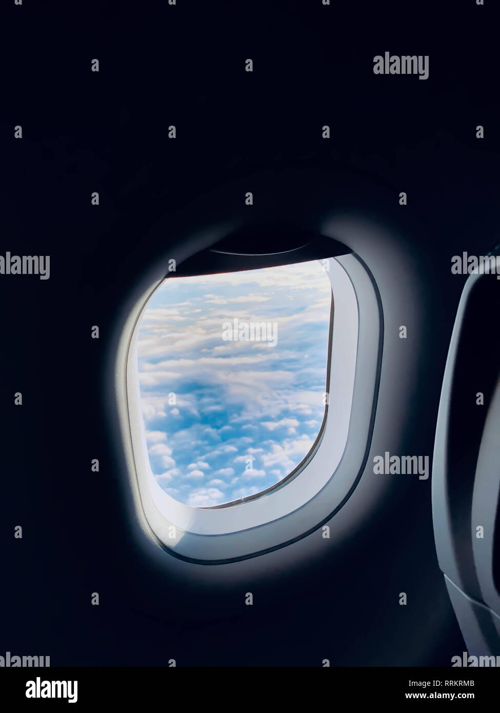 Detail of an airplane window with beautiful clouds outside, chiaroscuro ...