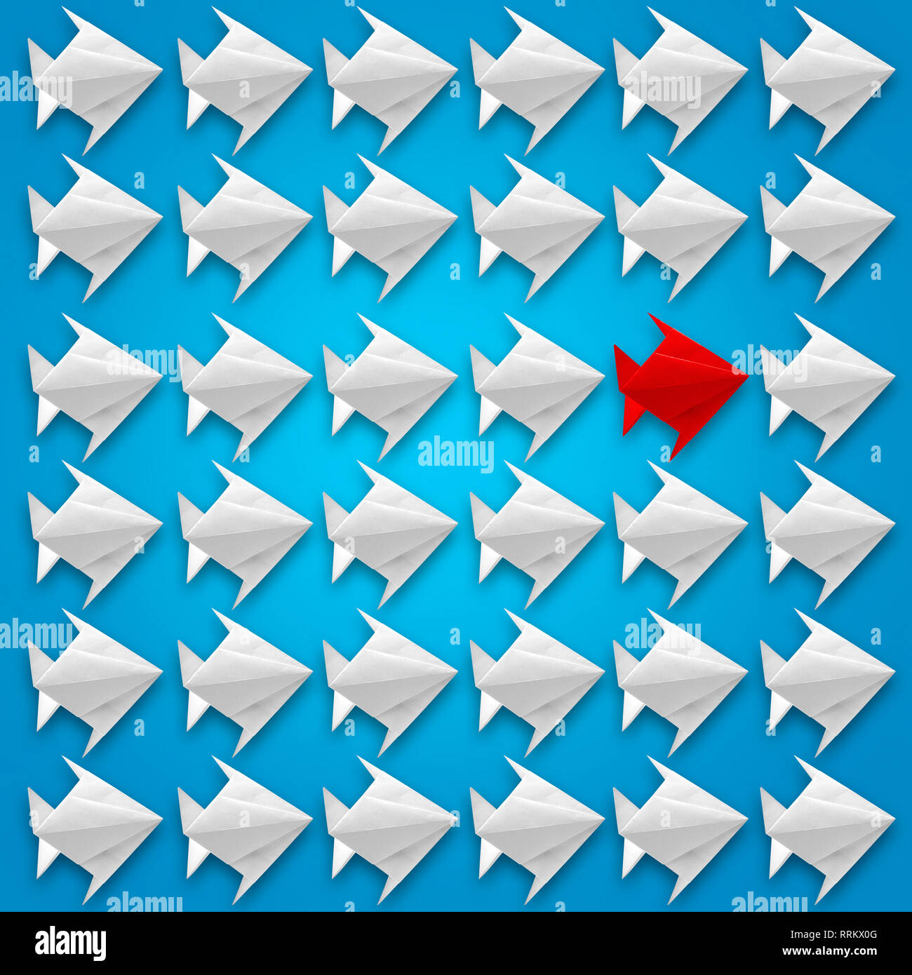 Flying paper fish origami with a red one on blue background. Business ...