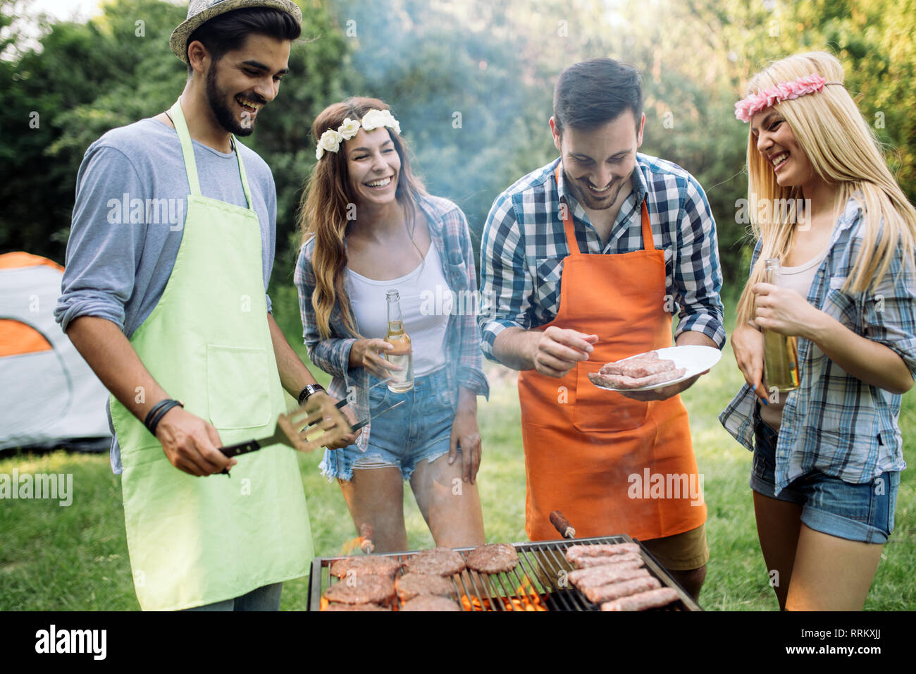 Group of friends making a barbecue together outdoors in the nature ...