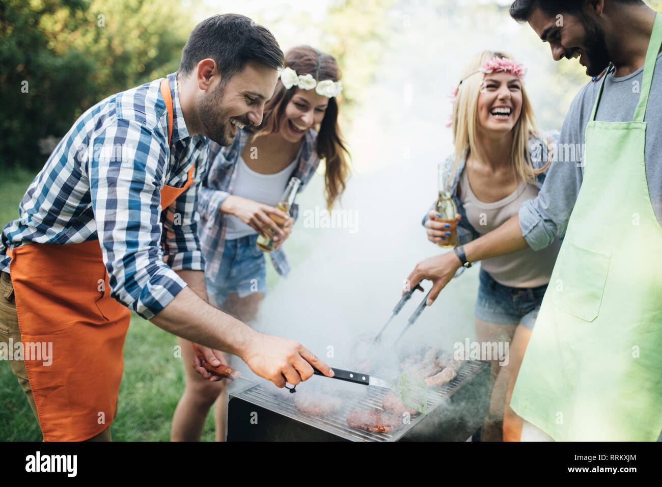 Group of friends making a barbecue together outdoors in the nature ...