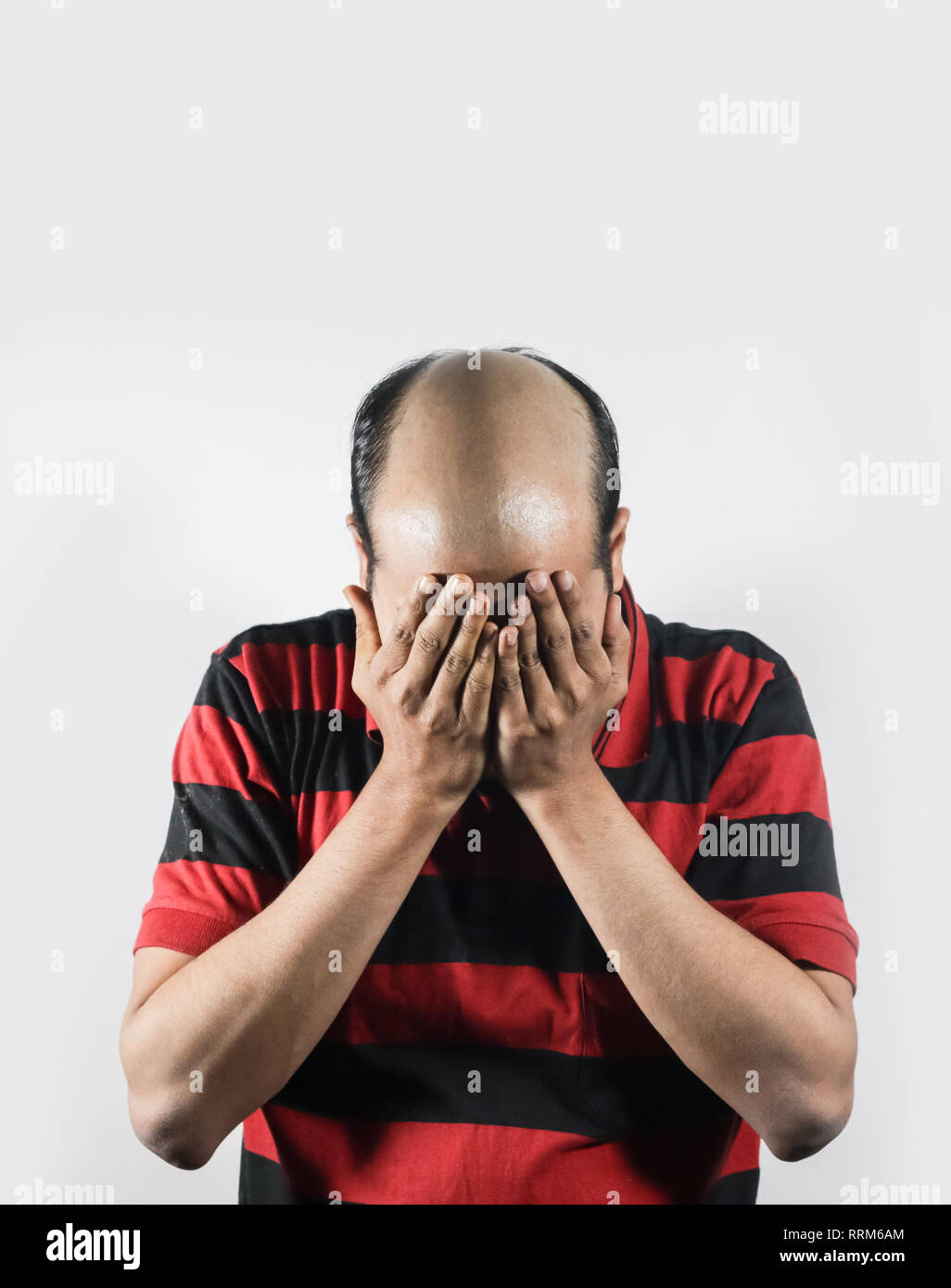 bald man covering his face in shame in white background with space for ...