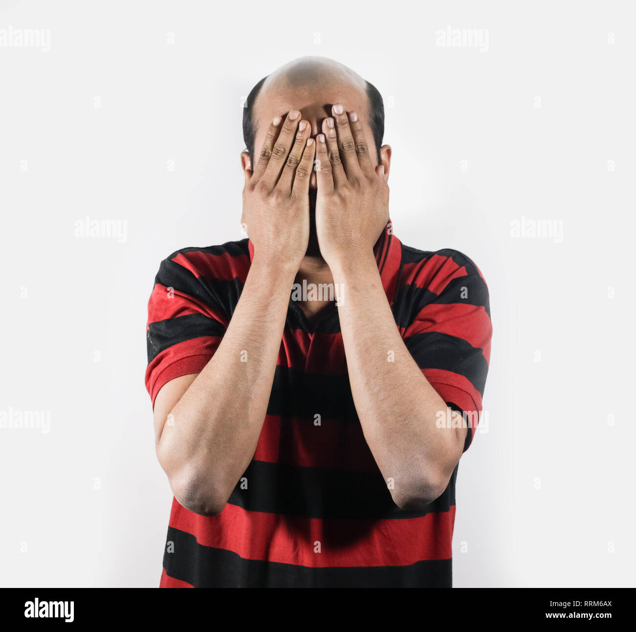 bald man covering his face in shame in white background with space for ...