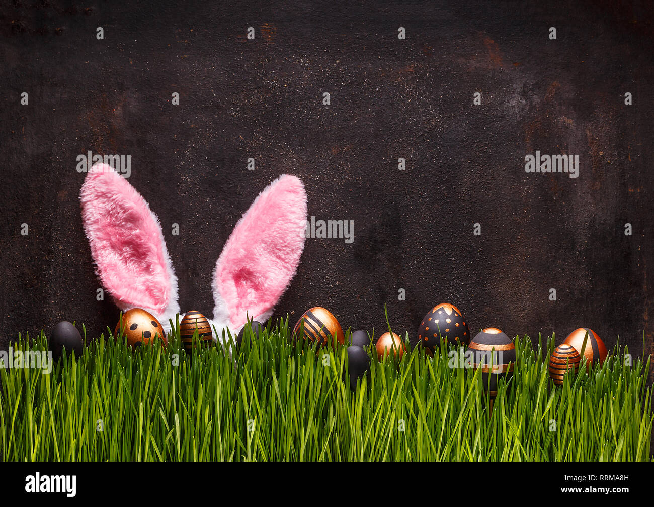 Cute Easter scene with pink rabbit ears and eggs hiding in green grass ...
