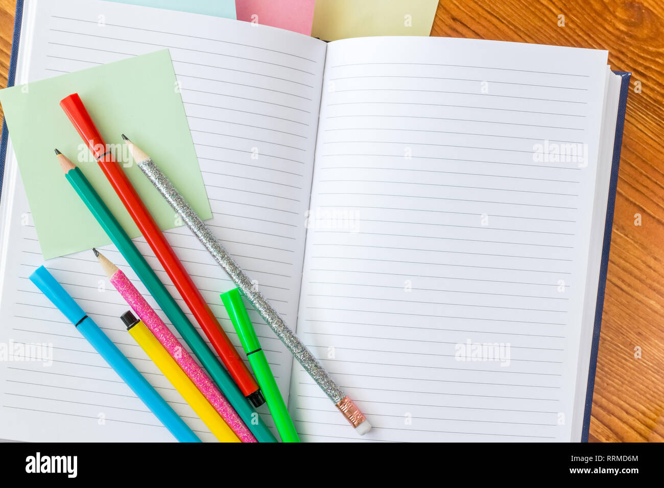 Colorful pencils and felt-tip pens on opened lined notebook Stock Photo ...