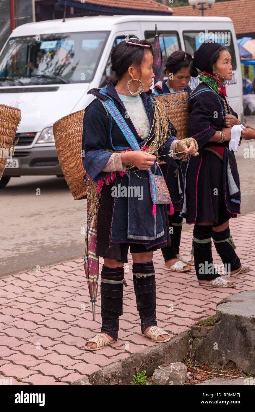 A local Hmong woman in traditional dress stands weaving rope, Sa Pa ...