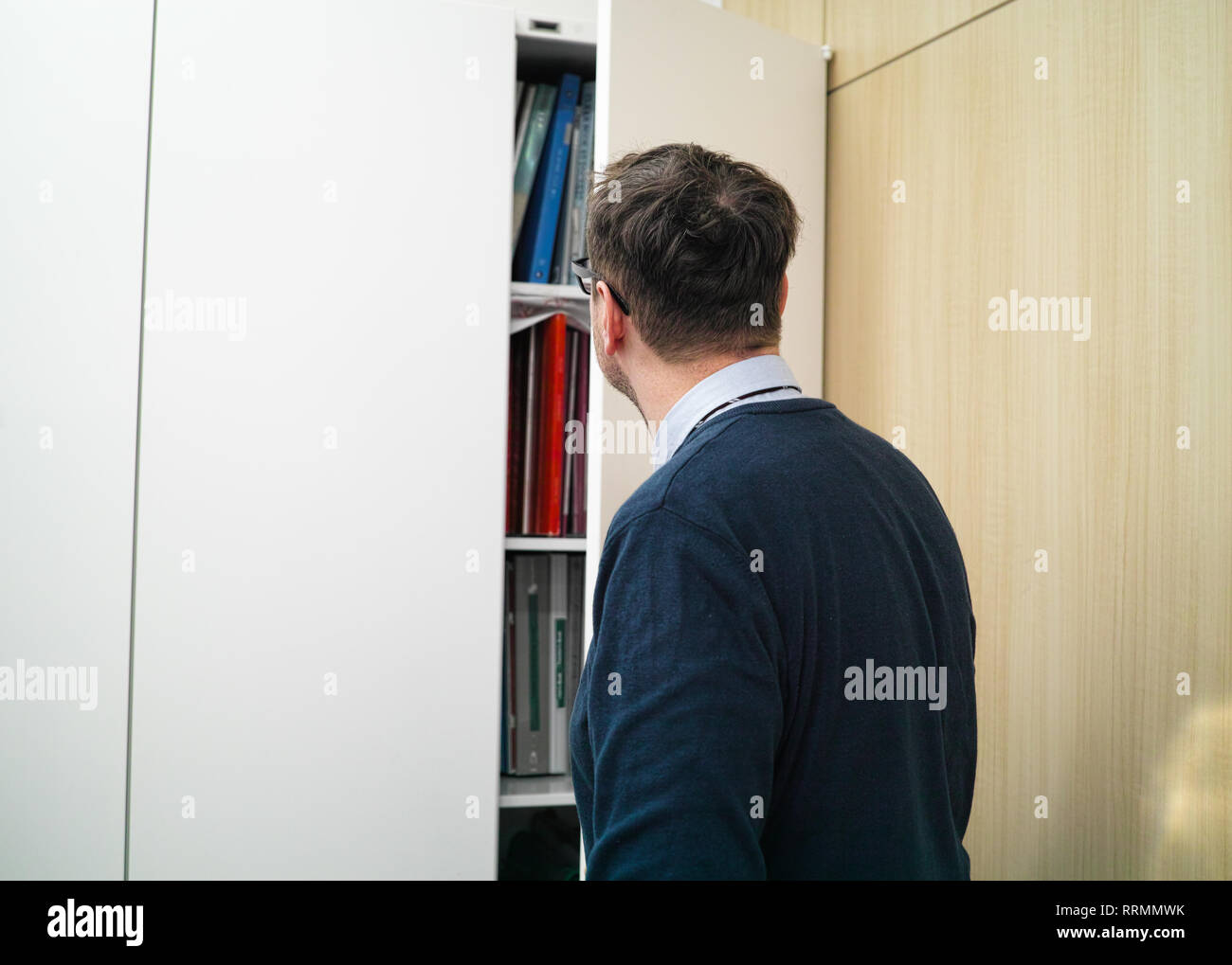 A man looking into a filing cabinet as he opens it Stock Photo - Alamy
