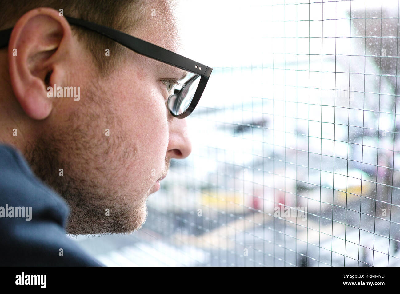 a man in glasses looking at the traffic out of the window with copy ...