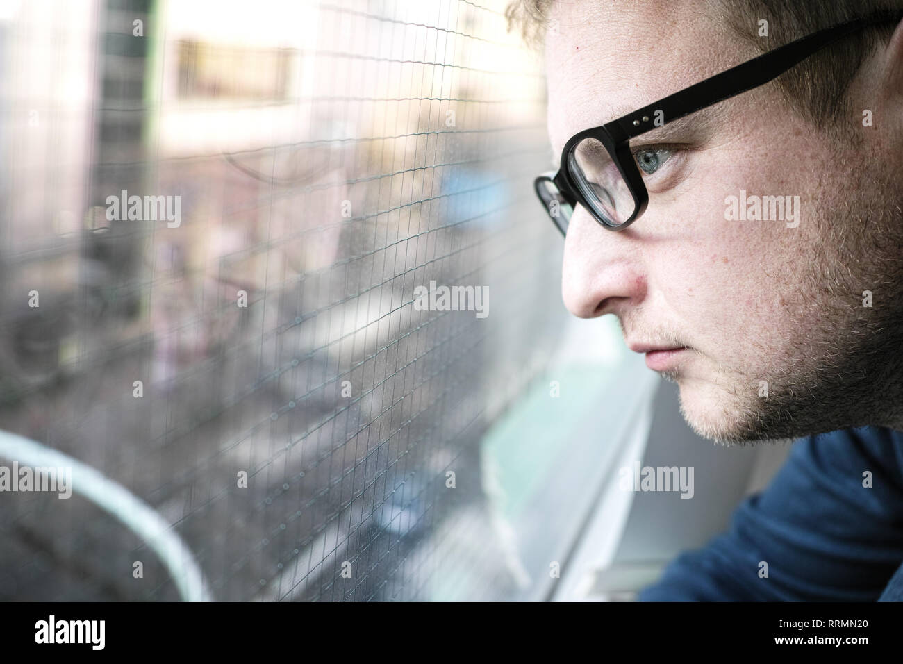 a man in glasses looking at the traffic out of the window with copy ...