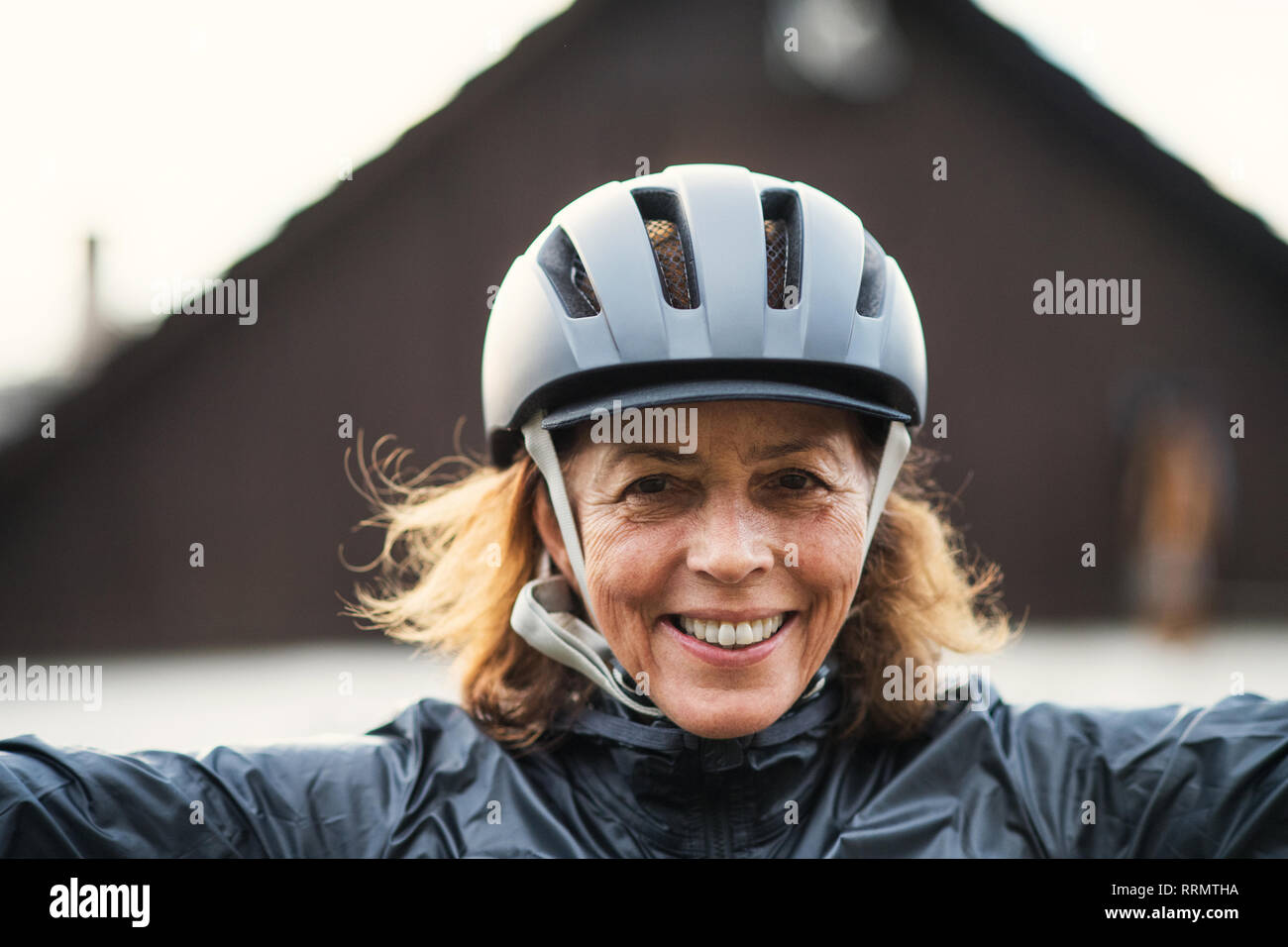 A front view portrait of cheerful active senior woman standing outdoors ...