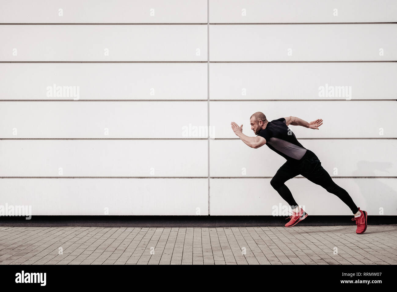 Side view of fit, sports man running by the wall with copy space Stock ...