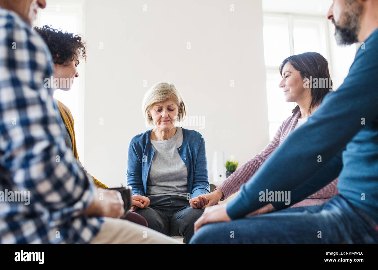 Men and women sitting in a circle and holding hands during group ...