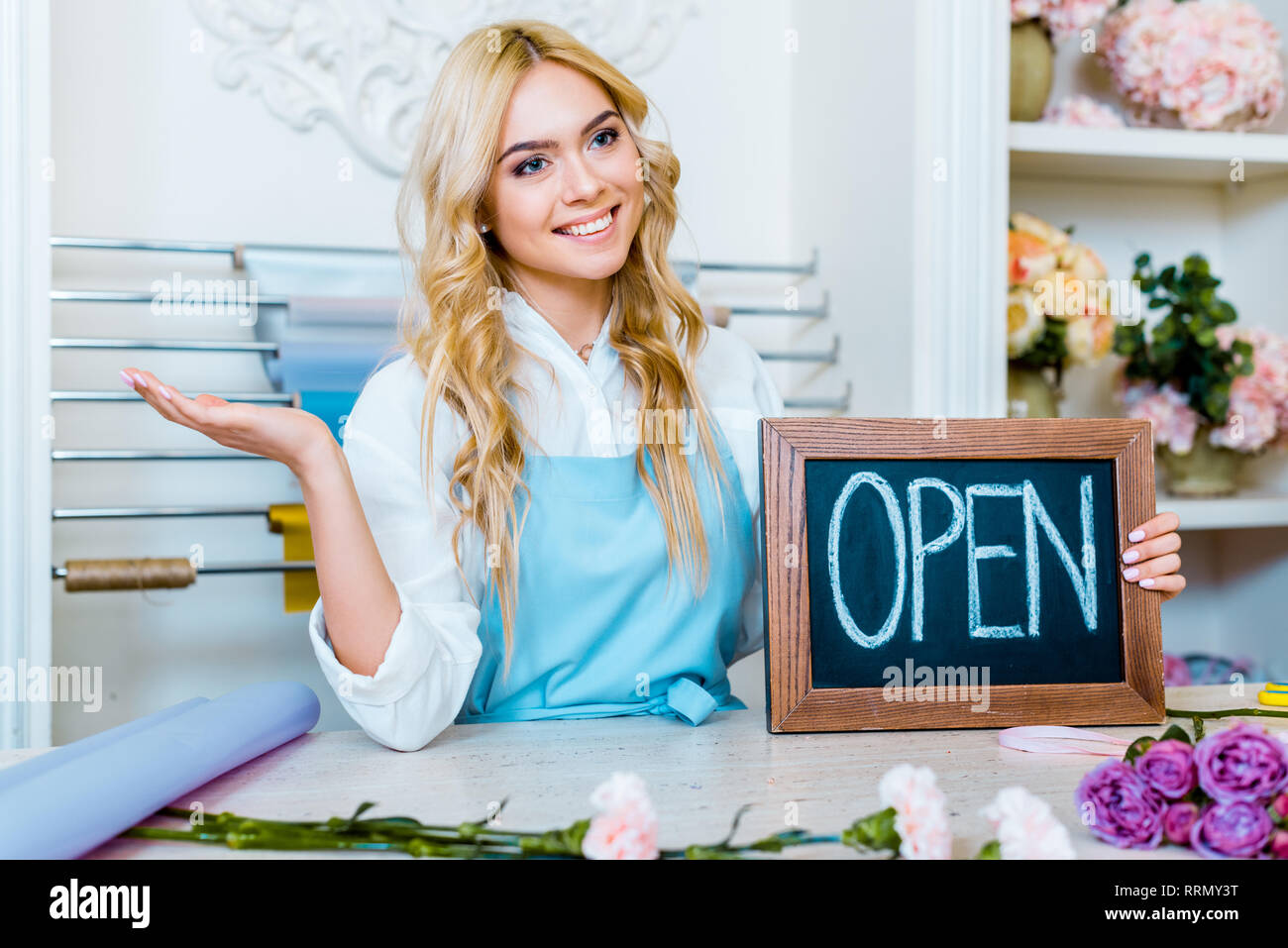beautiful smiling female flower shop owner gesturing with hand and ...