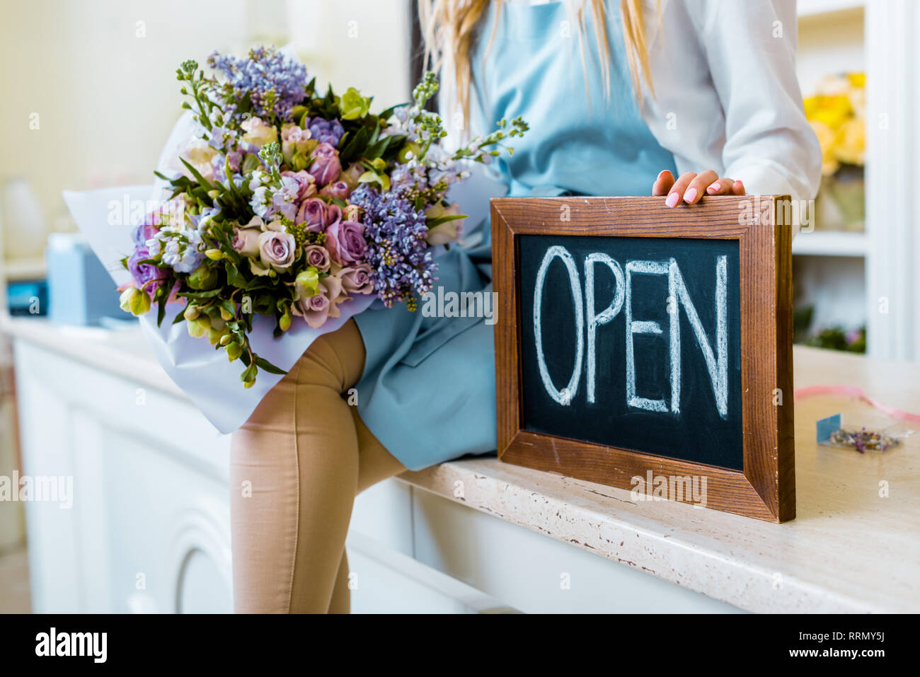 cropped view of female flower shop owner holding chalkboard with 'open ...