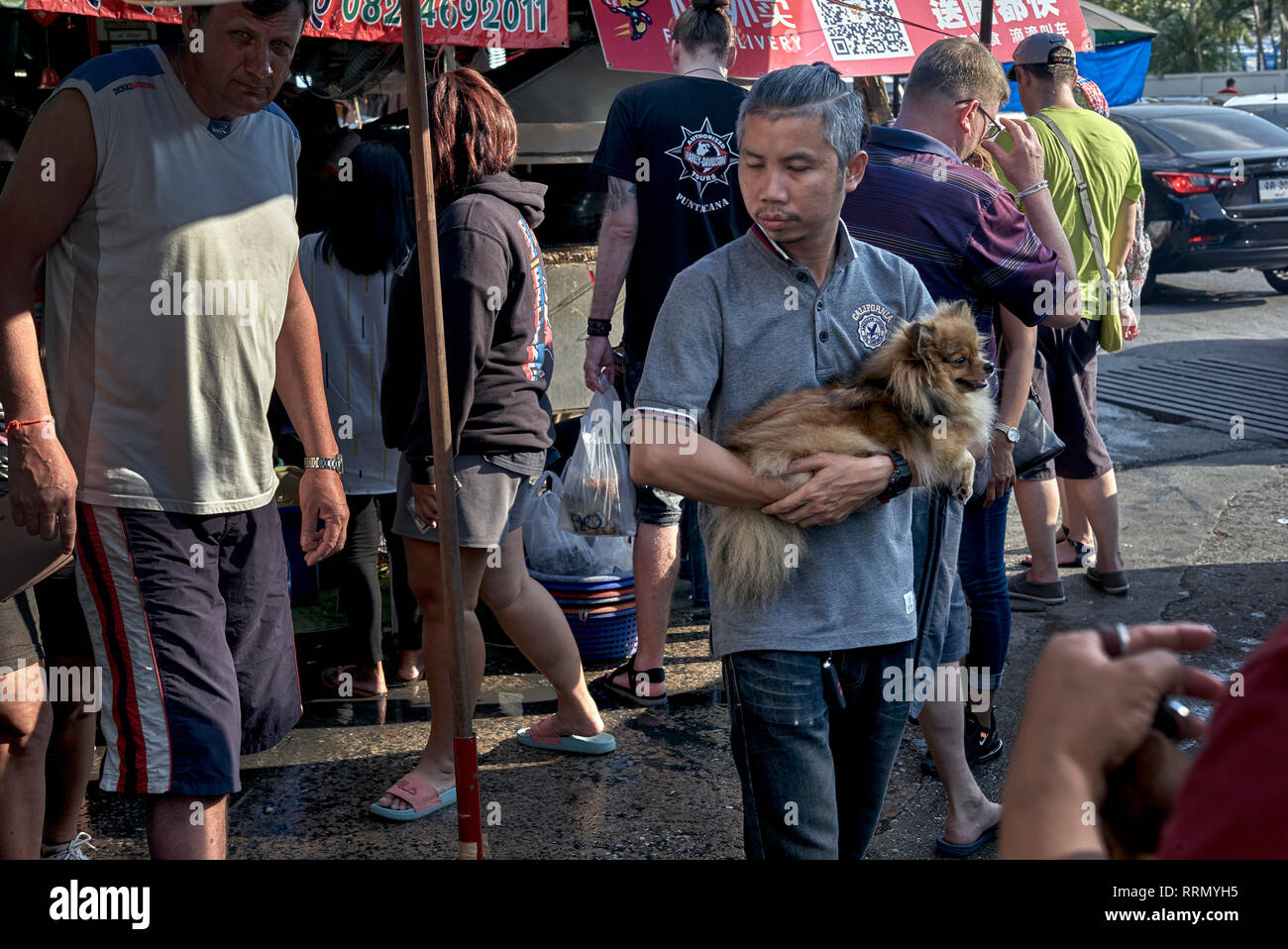 Man carrying dog whilst shopping at a Thailand street market Stock ...