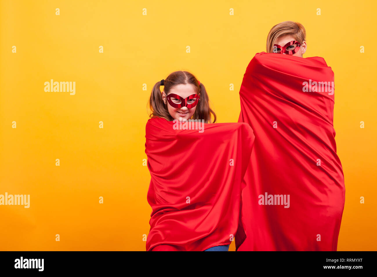 Beautiful mother with her daughter dressed like superheros hiding under ...