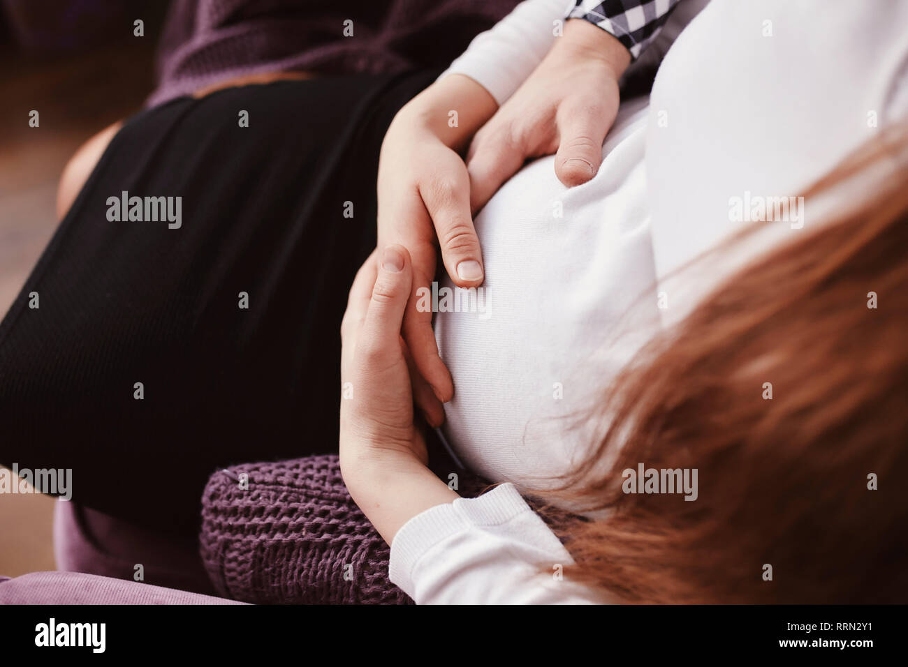 Young couple expecting baby hugging stomach Stock Photo - Alamy