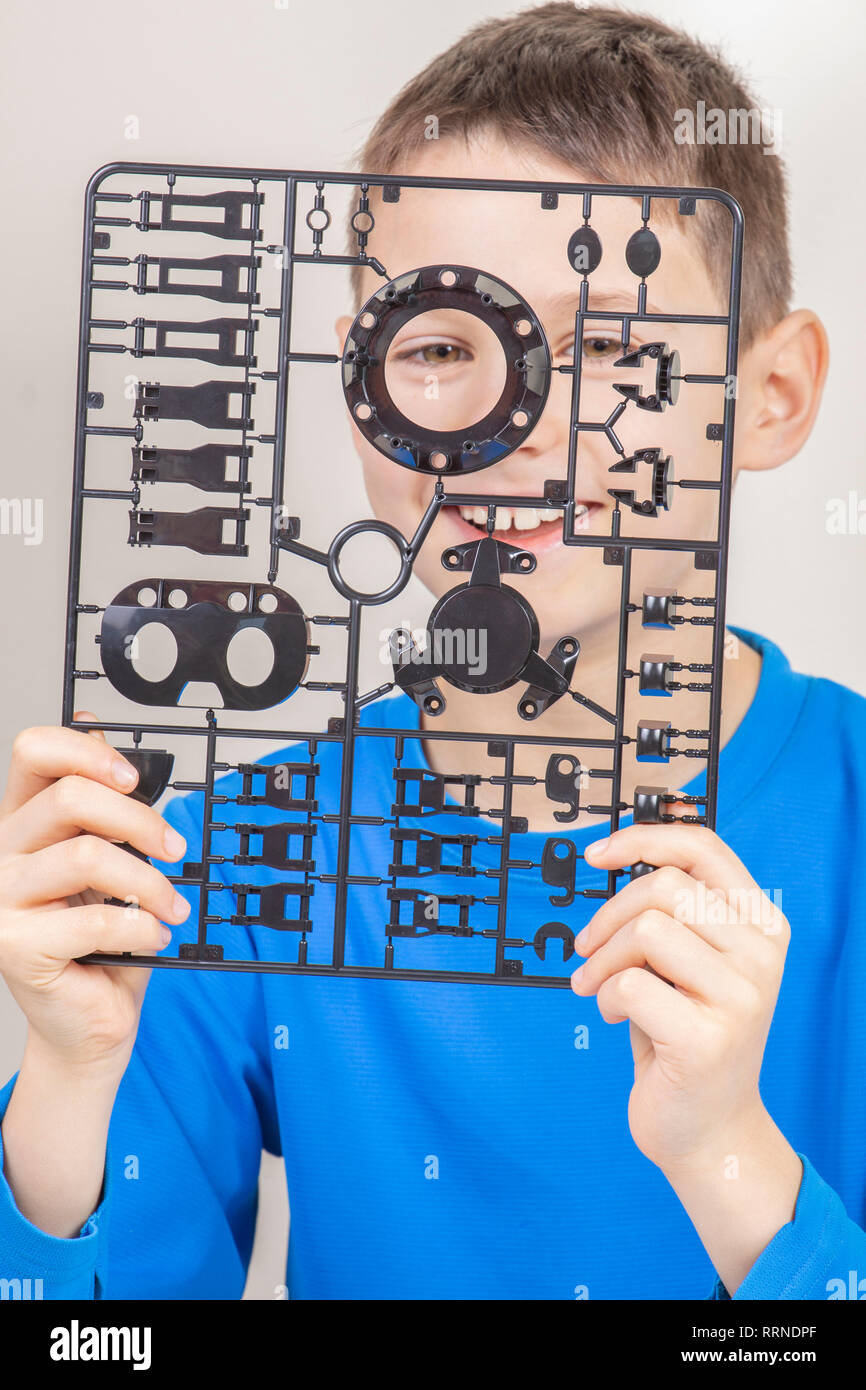 Kid having fun while making robot at home. Smiling boy with details of ...