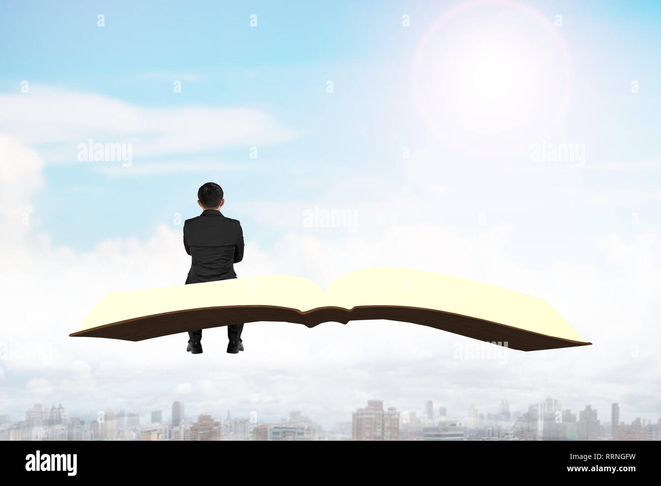 Man sitting on book flying over city in sky Stock Photo - Alamy