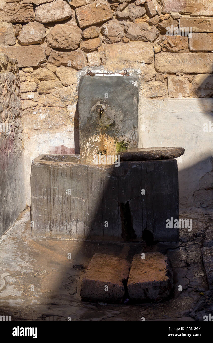 Old and damaged waterbasin on the street full of sunshine. Brick and ...