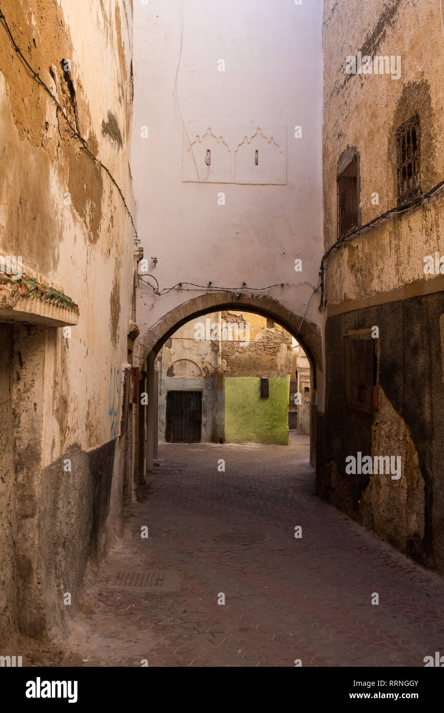 Dark morning narrow street with an arch city gate, made of stone bricks ...