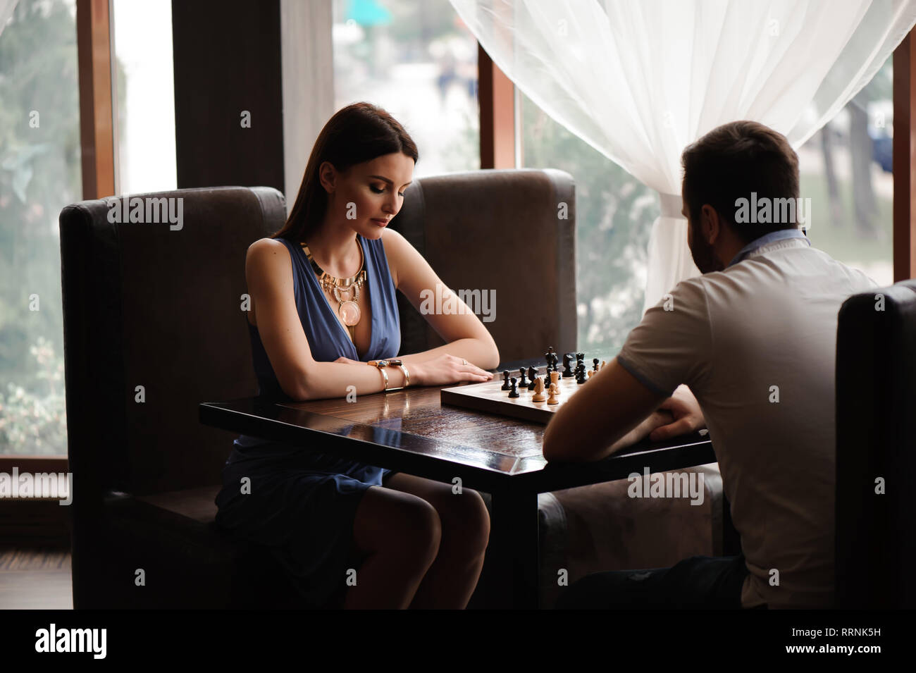 Young couple playing chess in the restaurant Stock Photo - Alamy