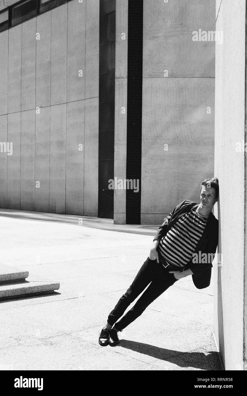 Portrait young man leaning against urban wall Stock Photo - Alamy