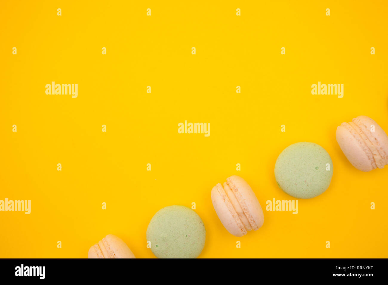 Row of colorful french macarons over yellow background. Sweet dessert ...