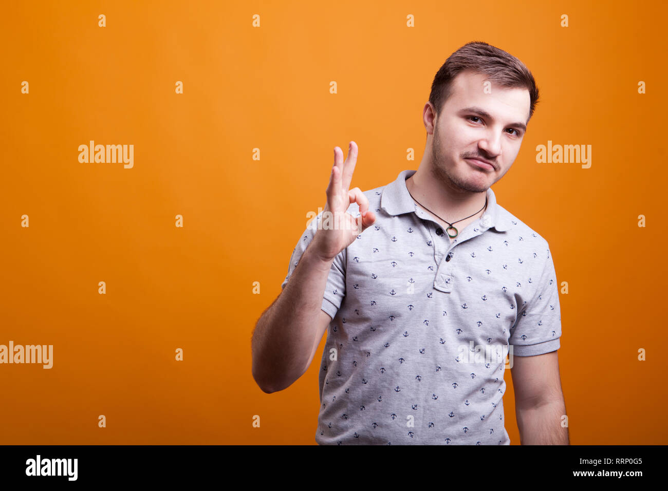 Young man showing the OK sign over yellow background. Positive young ...