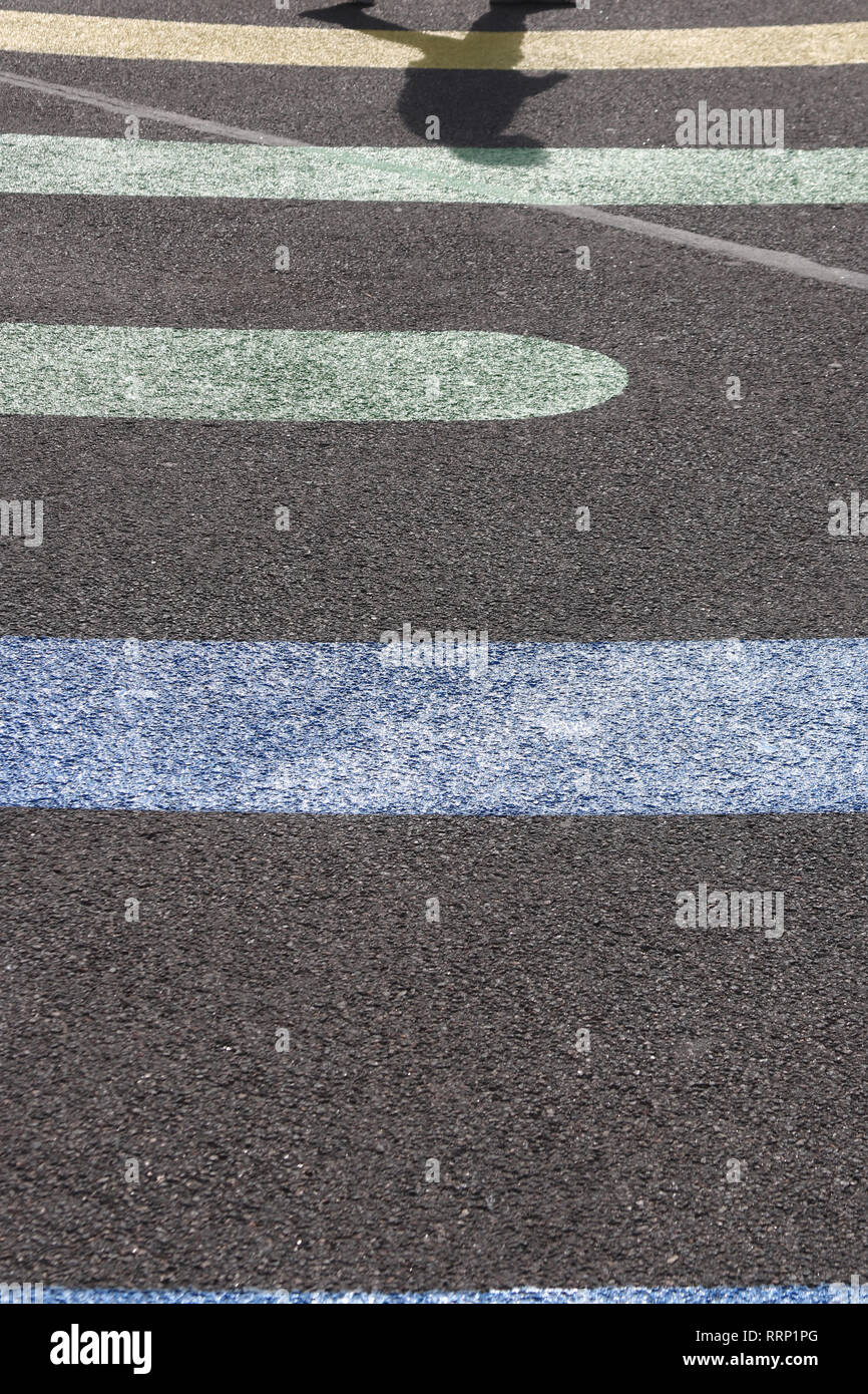 Walking man shadow on colored line shapes on asphalt surface texture ...