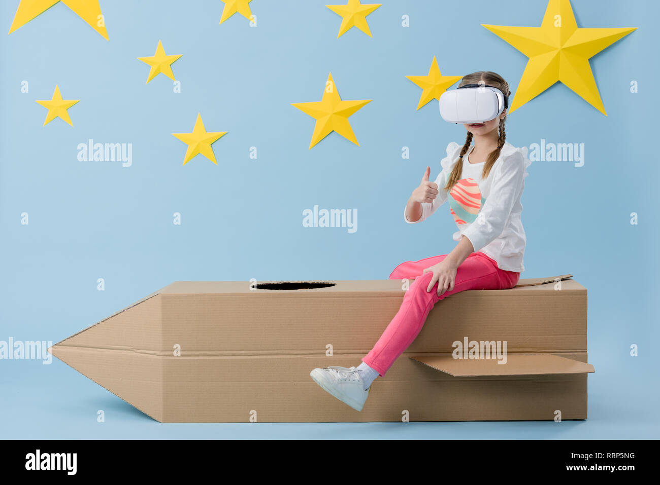 Kid in vr headset sitting on cardboard rocket and showing thumb up on ...
