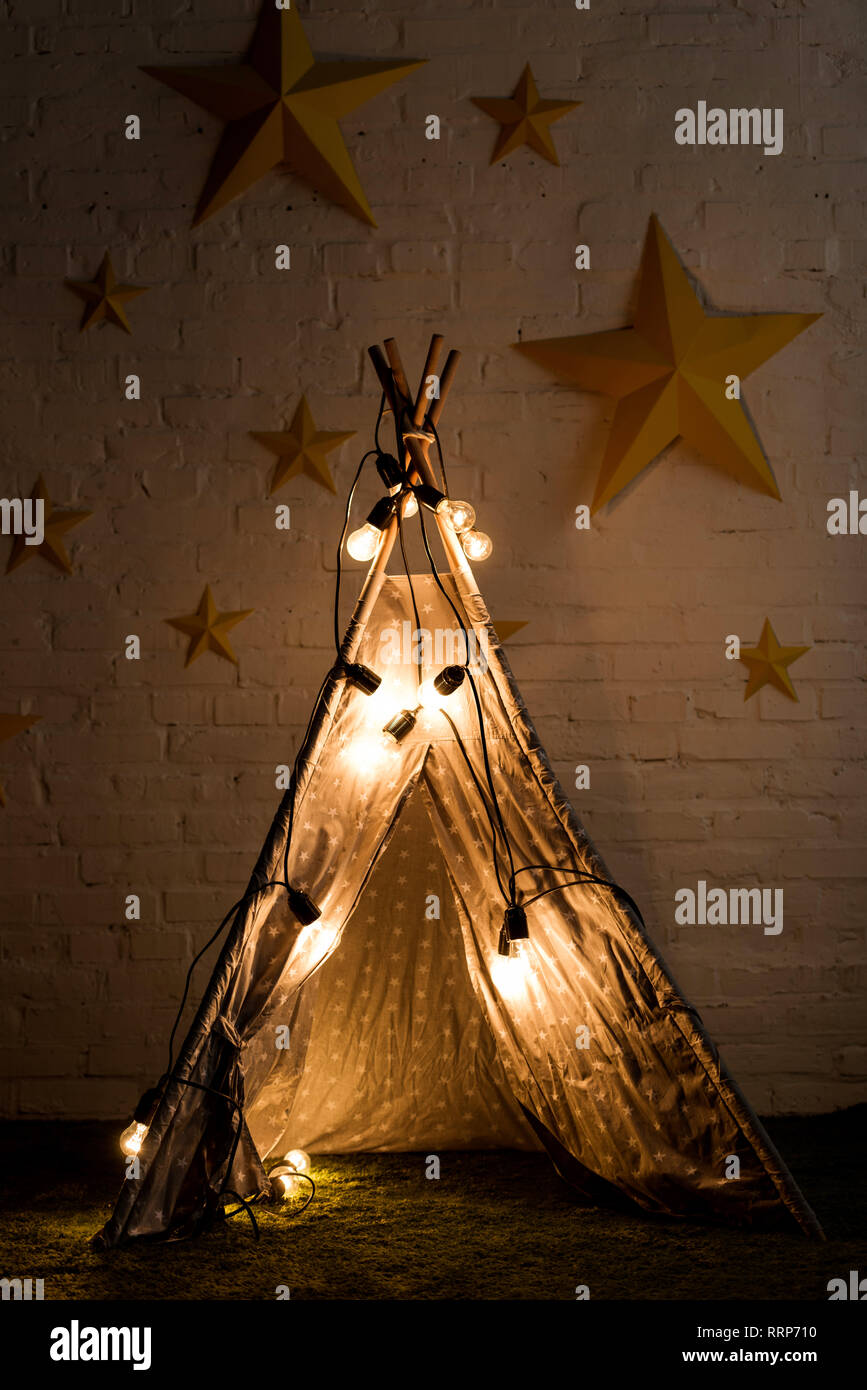 Cozy wigwam with luminous bulbs standing in dark room Stock Photo - Alamy