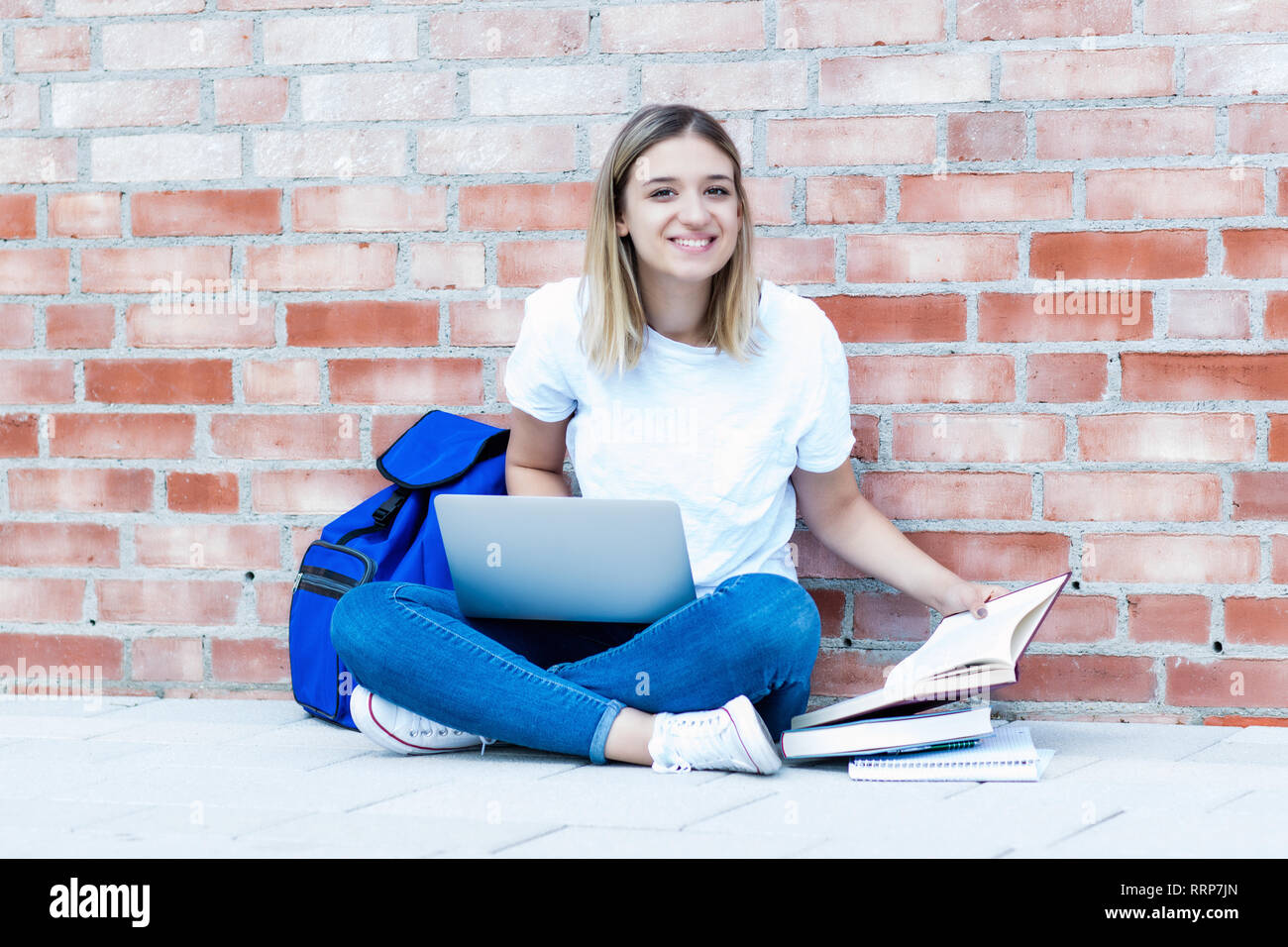 German female student learning at computer outdoor on campus of ...