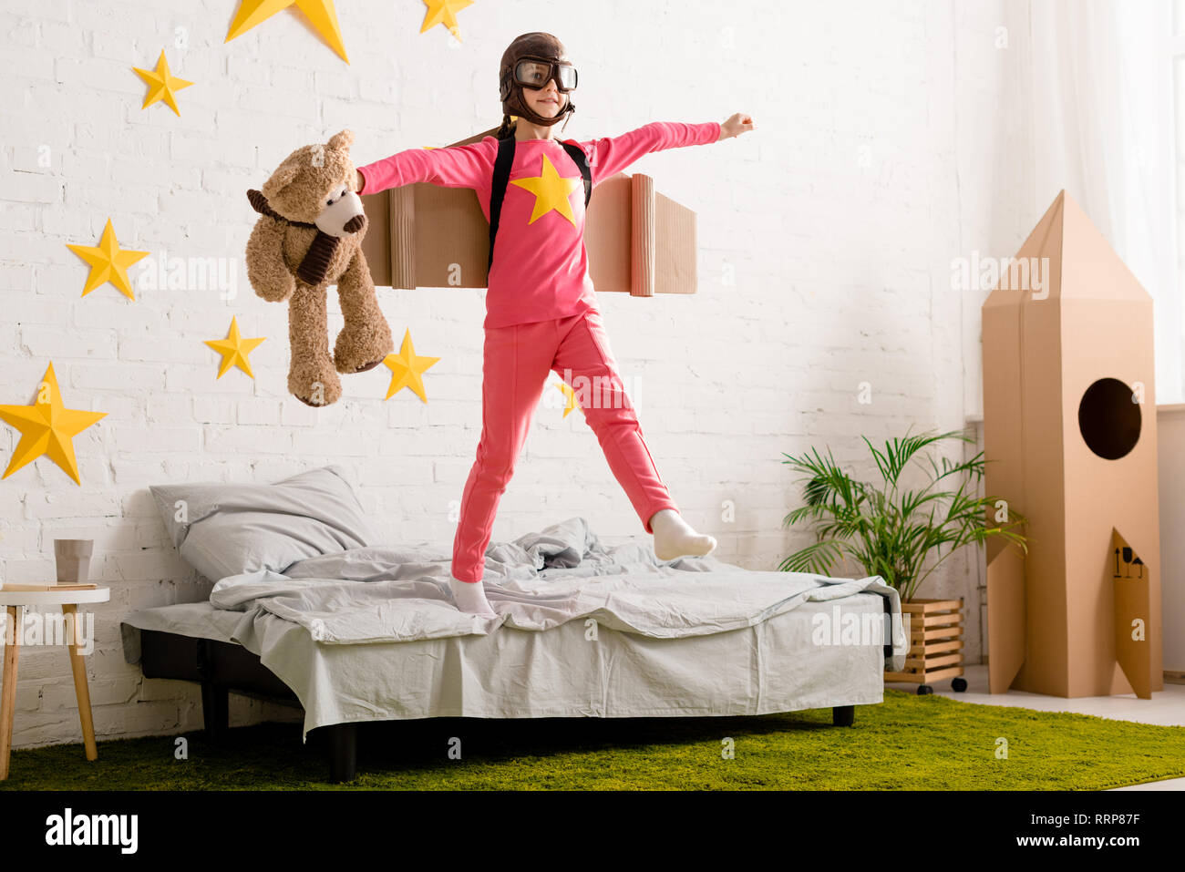 Funny kid with teddy bear jumping on bed Stock Photo - Alamy