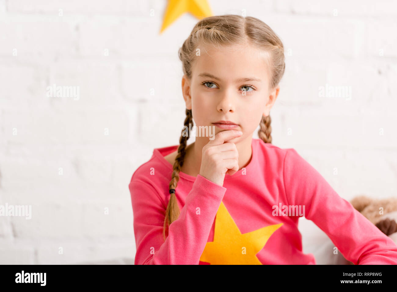 Pensive kid with braids touching chin and looking away Stock Photo - Alamy