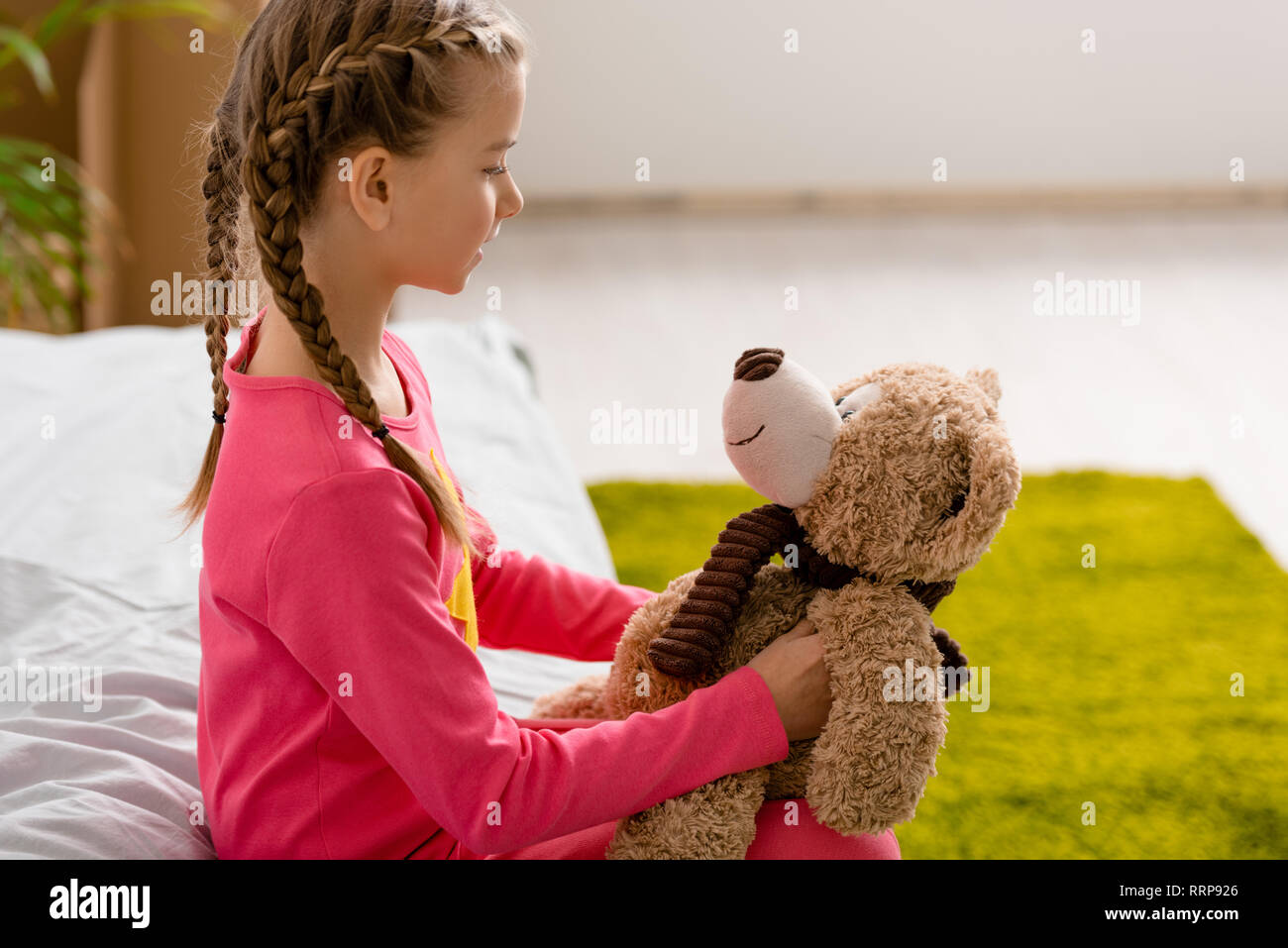 Side view of child with braids looking at teddy bear Stock Photo - Alamy