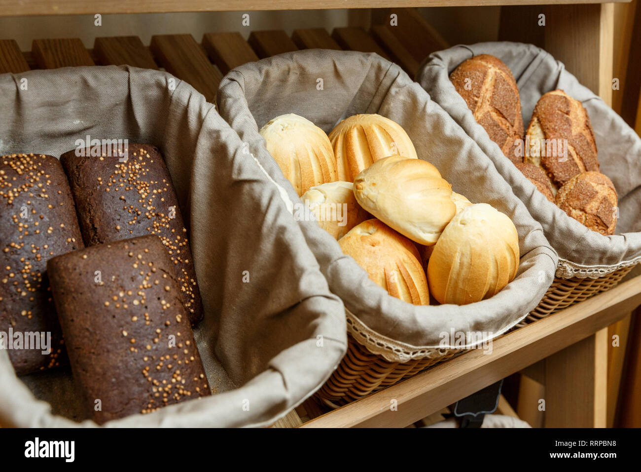 Assortment of fresh bread in baskets on the shelves in bakery Stock ...