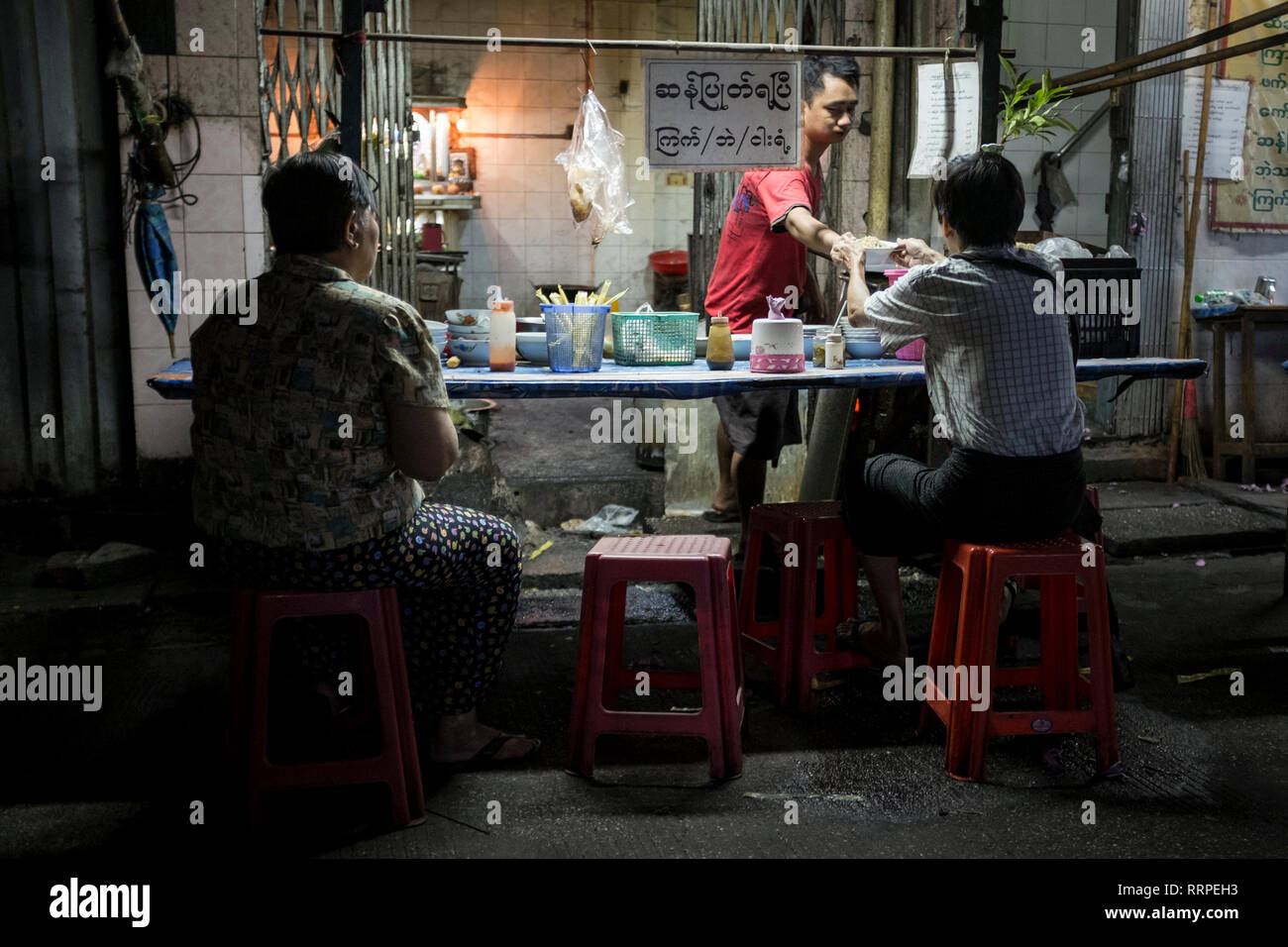 Yangon, Myanmar - 19 September 2016: Two men eating at a street food ...