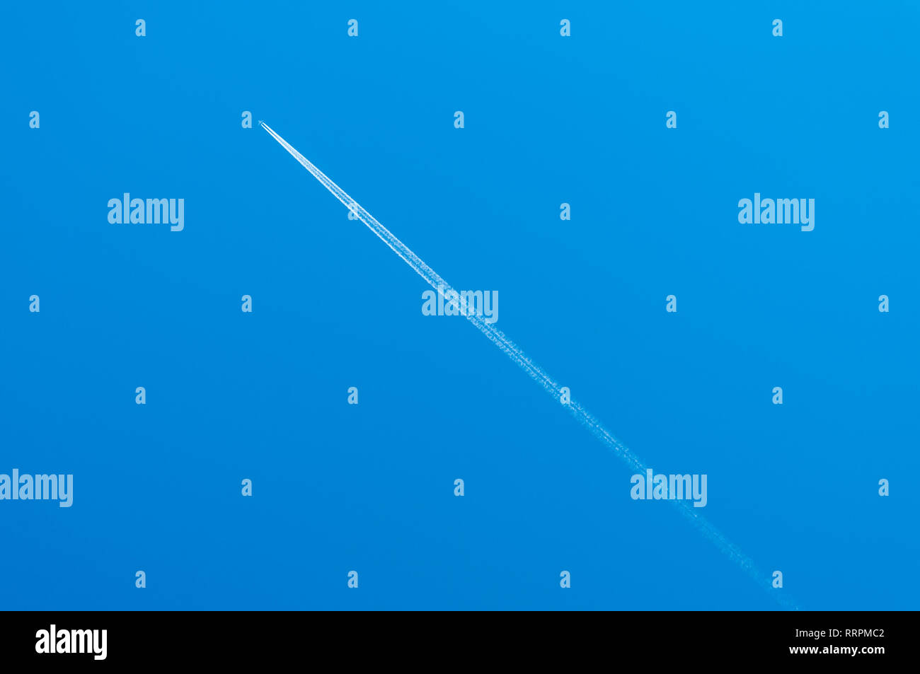 white streaks of a plane in the blue sky Stock Photo - Alamy