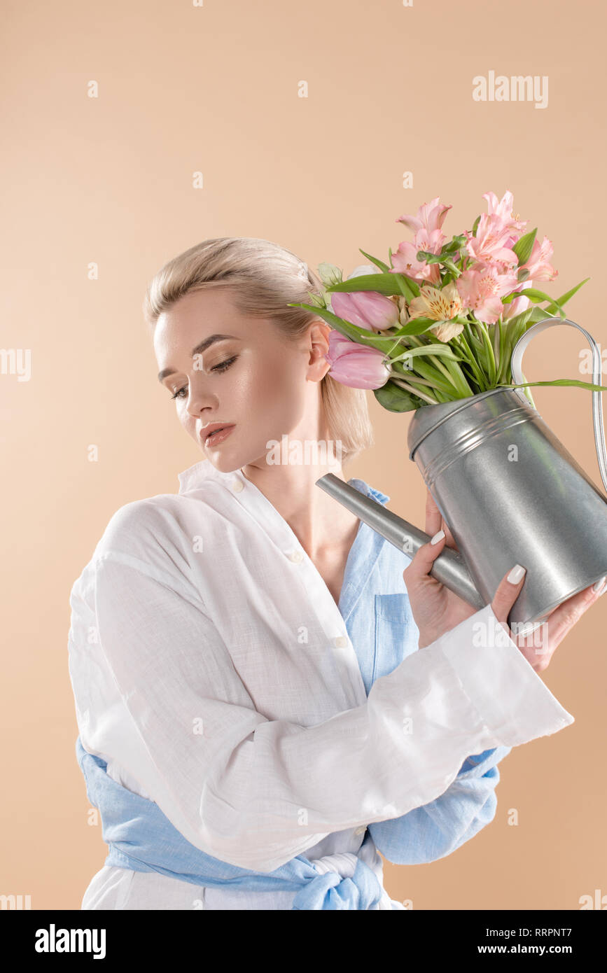 woman holding watering can with flowers and standing in eco clothing ...