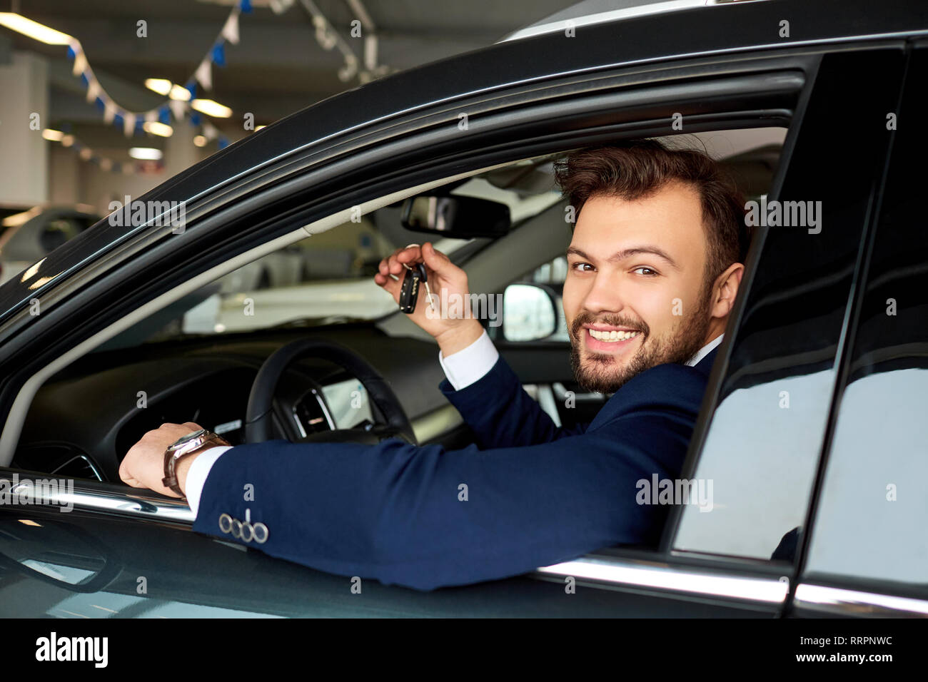 Male driver smiling holds the keys to the car Stock Photo - Alamy