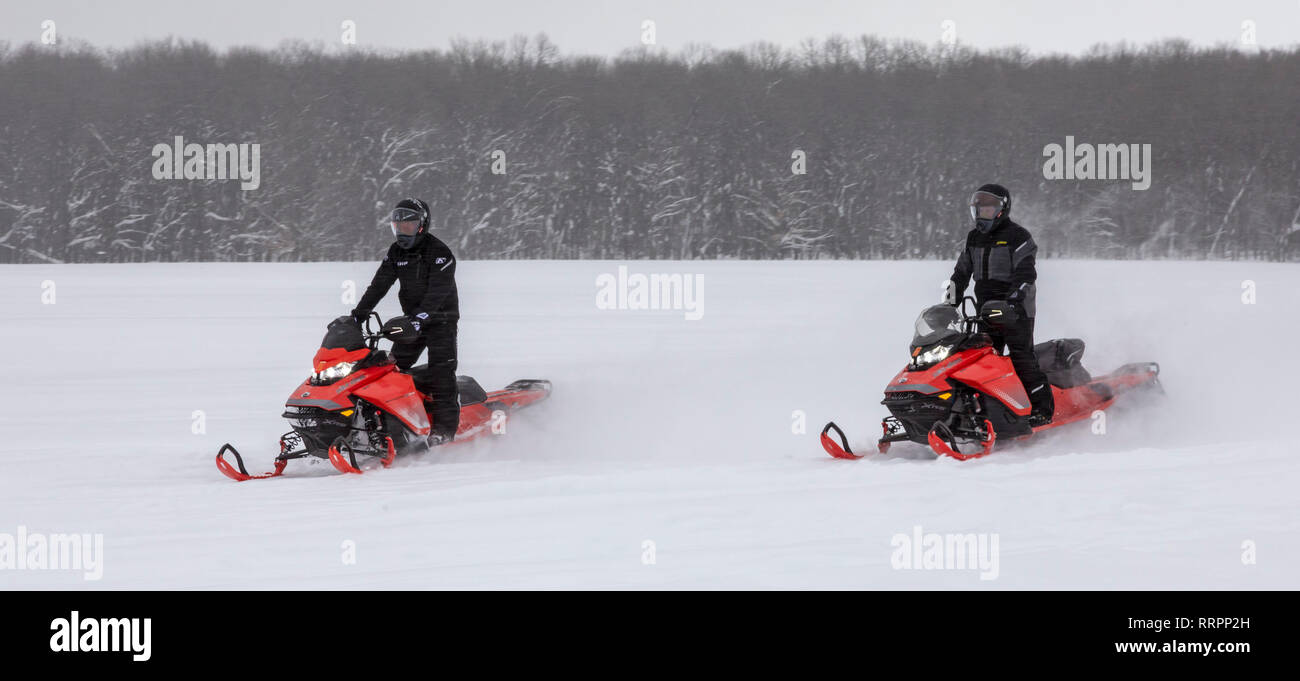 Eben Junction, Michigan - Snowmobiles race across a snow-covered farm ...