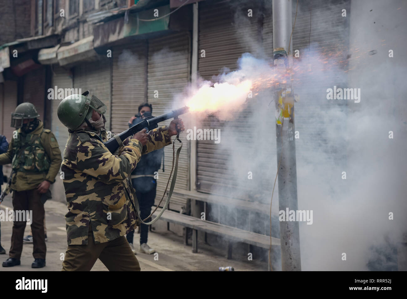 Indian policemen are seen lobbing tear gas smoke shell towards the ...