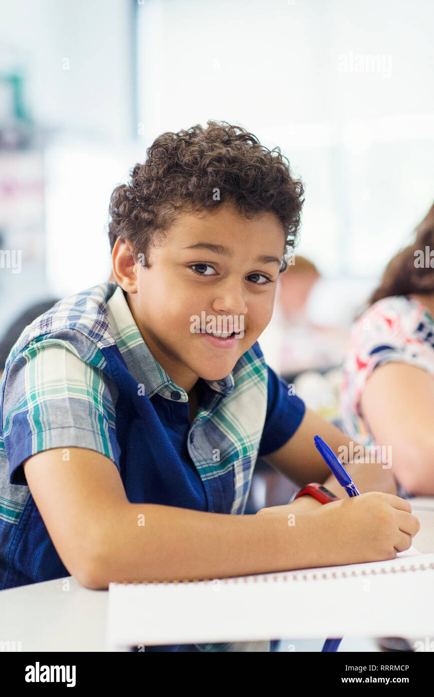Portrait confident elementary age boy doing homework in classroom Stock ...