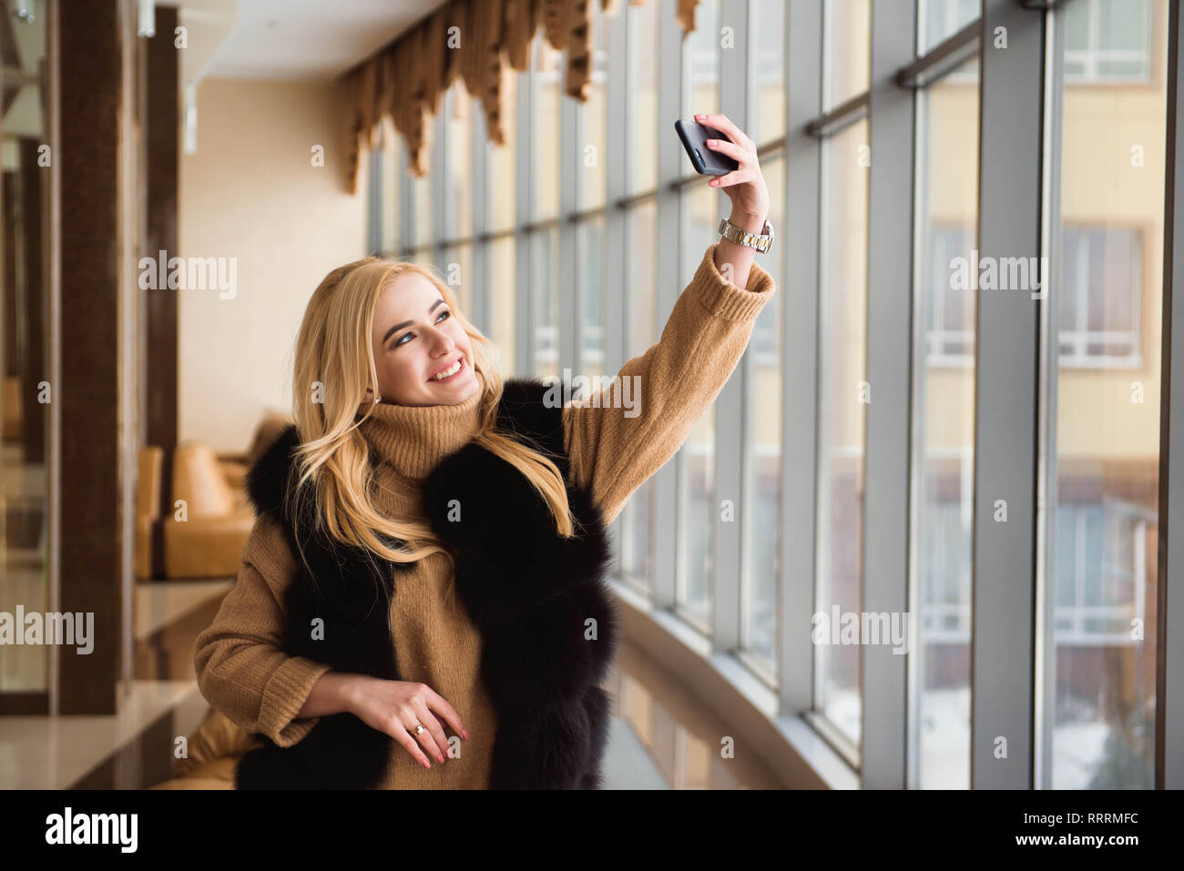Beautiful blonde girl doing selfie by the window Stock Photo - Alamy