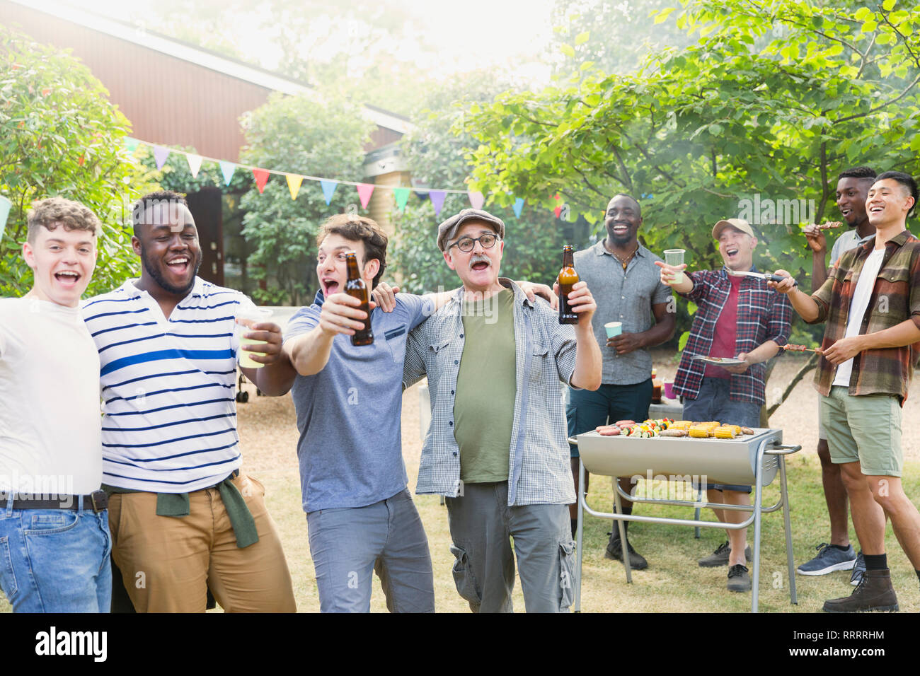 Happy, exuberant male friends drinking beer and singing during backyard ...