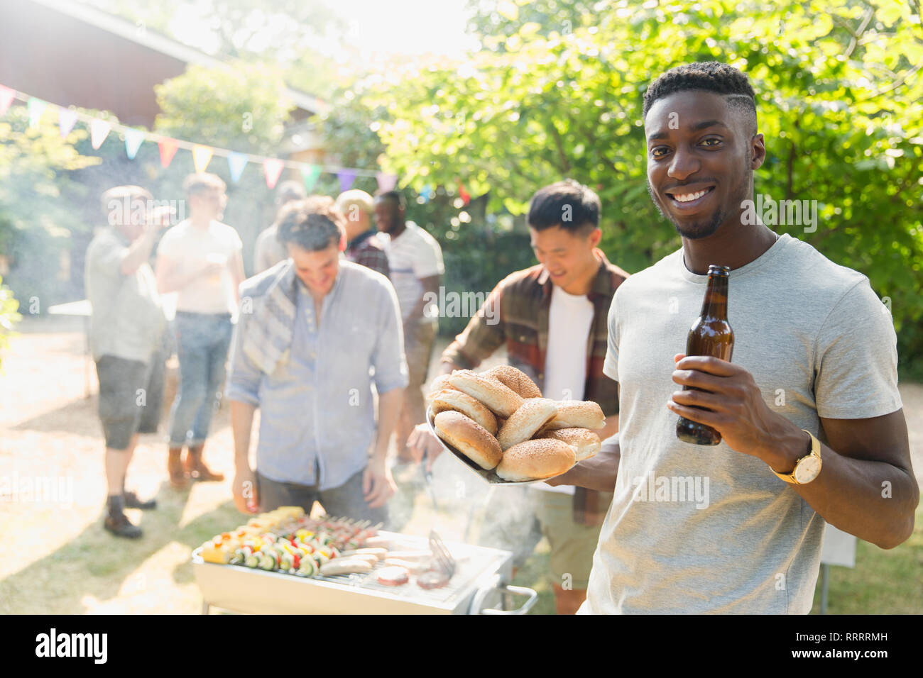 Portrait confident young man drinking beer, enjoying barbecue in summer ...