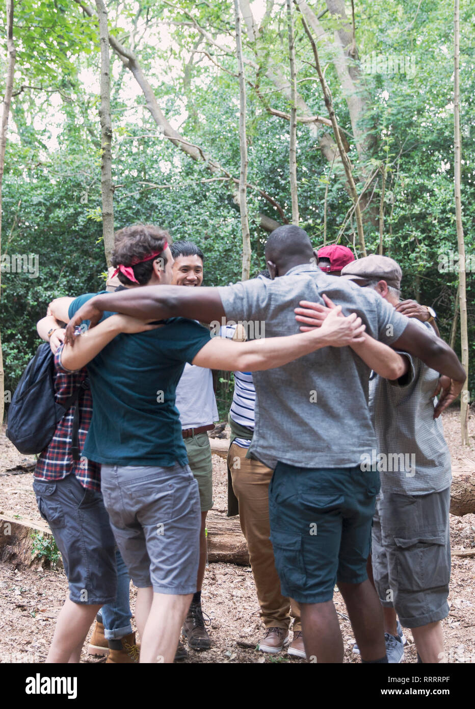 Mens group hugging in huddle, hiking in woods Stock Photo - Alamy