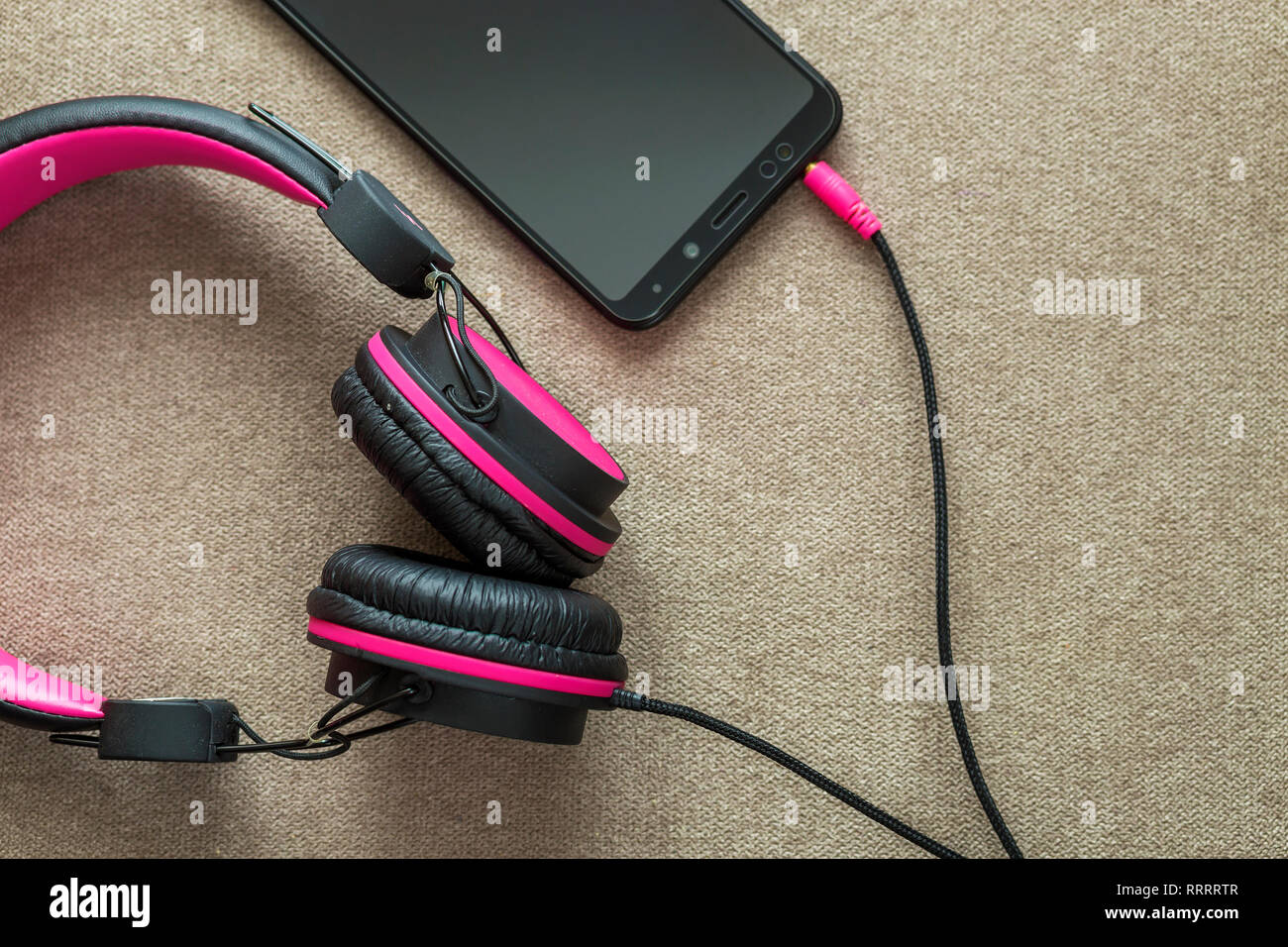 Headphone connected to cellphone isolated on light cloth flat copy ...