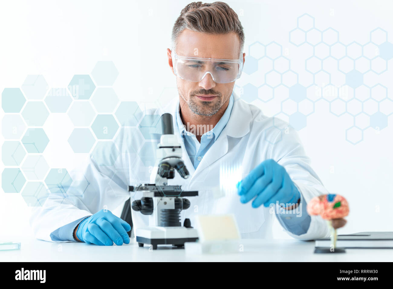 selective focus of handsome scientist in protective glasses making ...