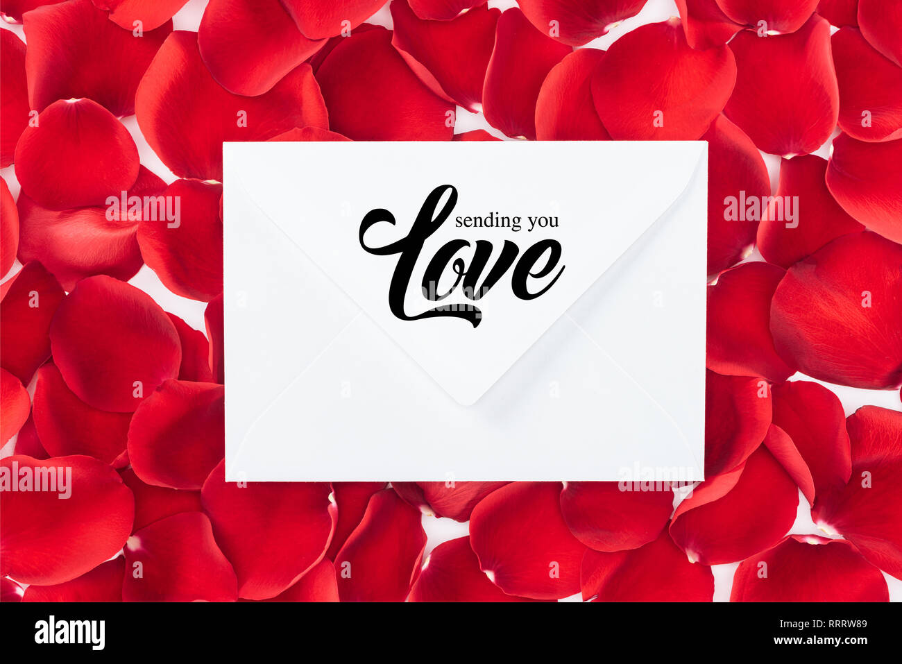 top view of envelope with "sending you love" lettering and red rose ...